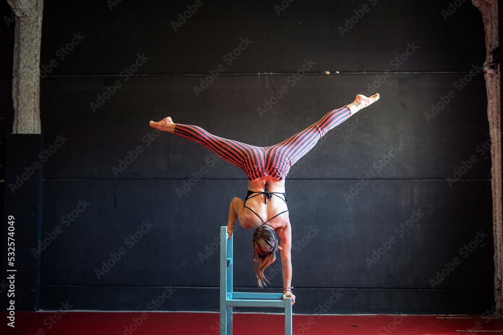 Anonymous circus woman doing an inverted handstand on a chair. Stock ...