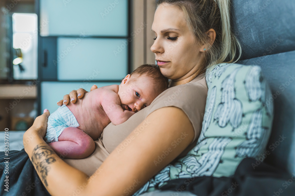 White blond woman lying in bed cuddling with her newborn baby boy ...