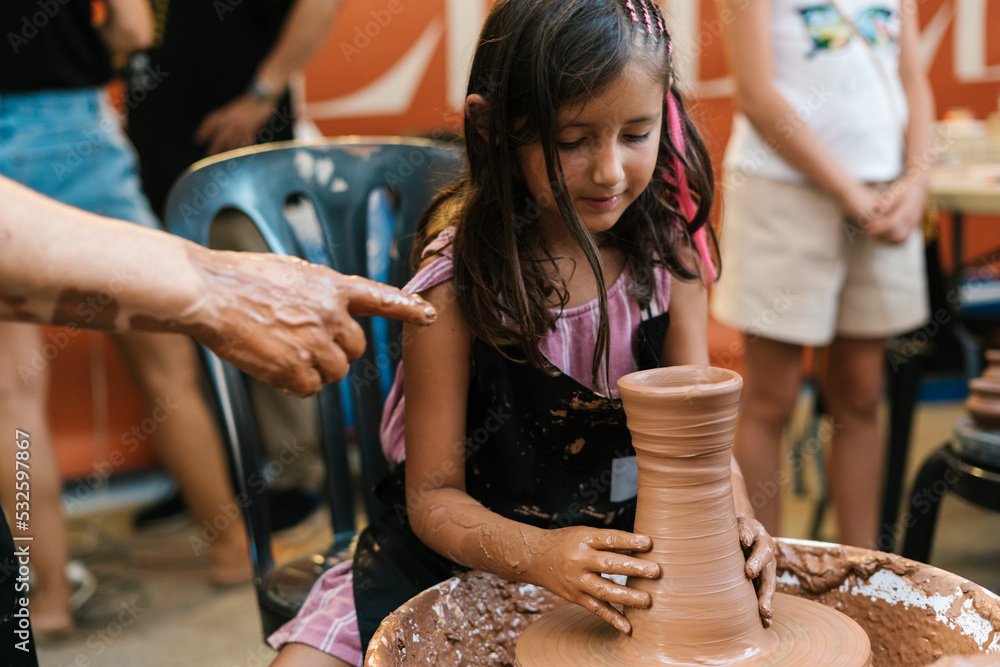 Faceless person pointing near girl making clay vessel Stock Photo ...