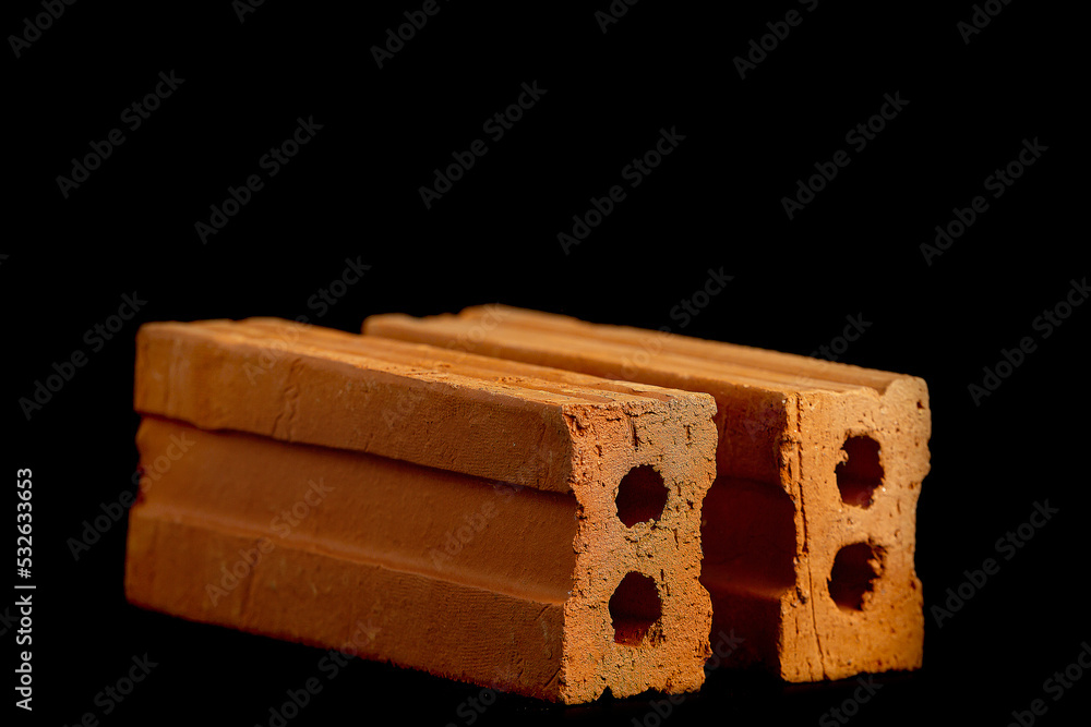 Solid clay bricks used in construction are laid on a black background ...