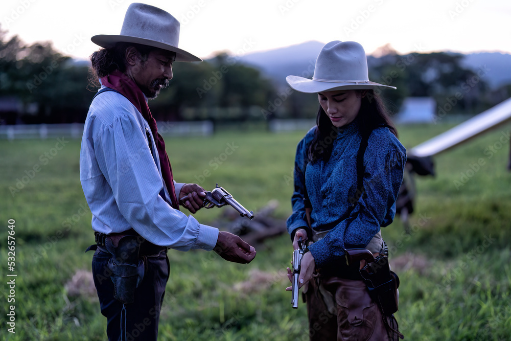 Cowboy man standing at the green land near mountain side teaching cow ...