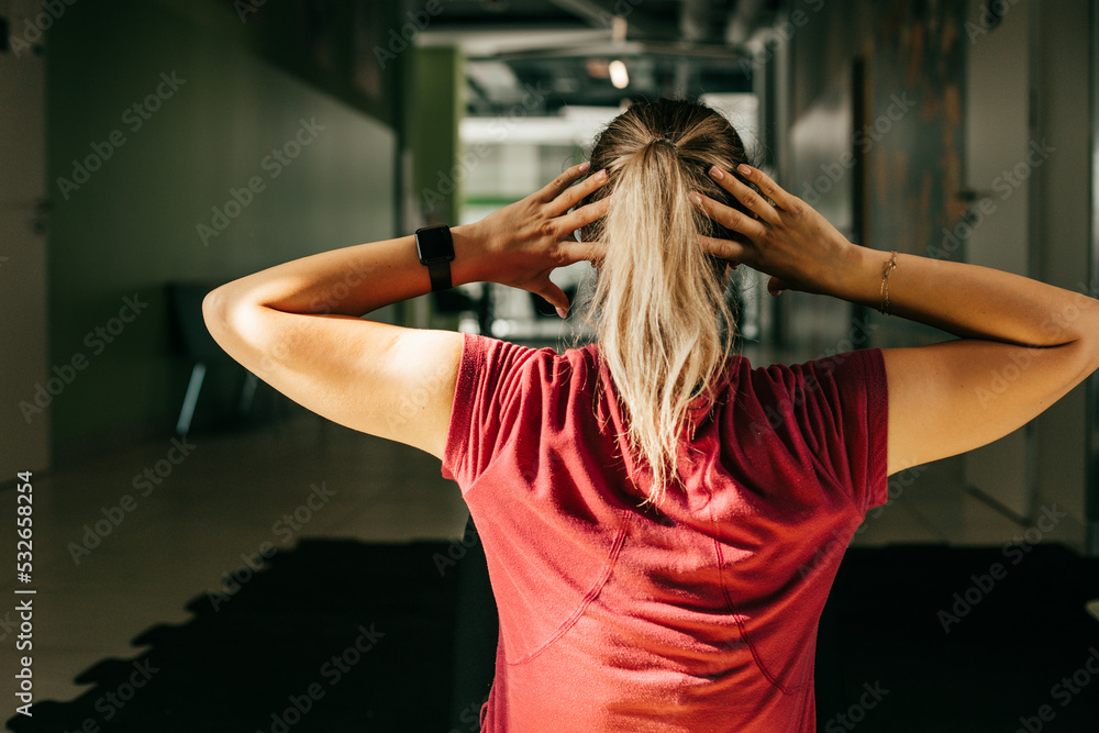 Girl with hair tied in ponytail pump press in fitness gym keeping hands ...
