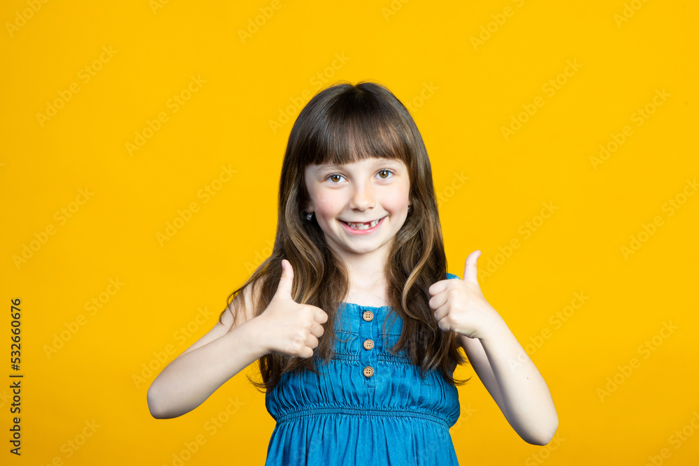 A little smiling girl raised her finger thumb up and shows Cool, Super ...