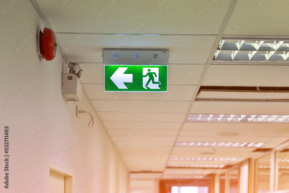 Green emergency exit sign showing the way to escape. Fire exit in the ...