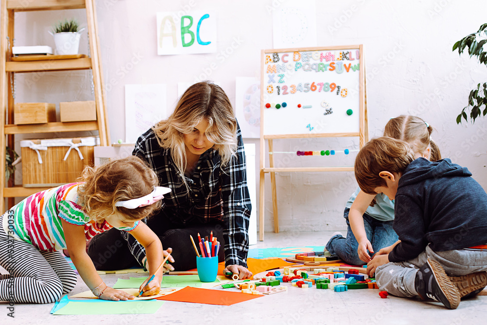 Little kids and educator folding Bricks and drawing with colored ...