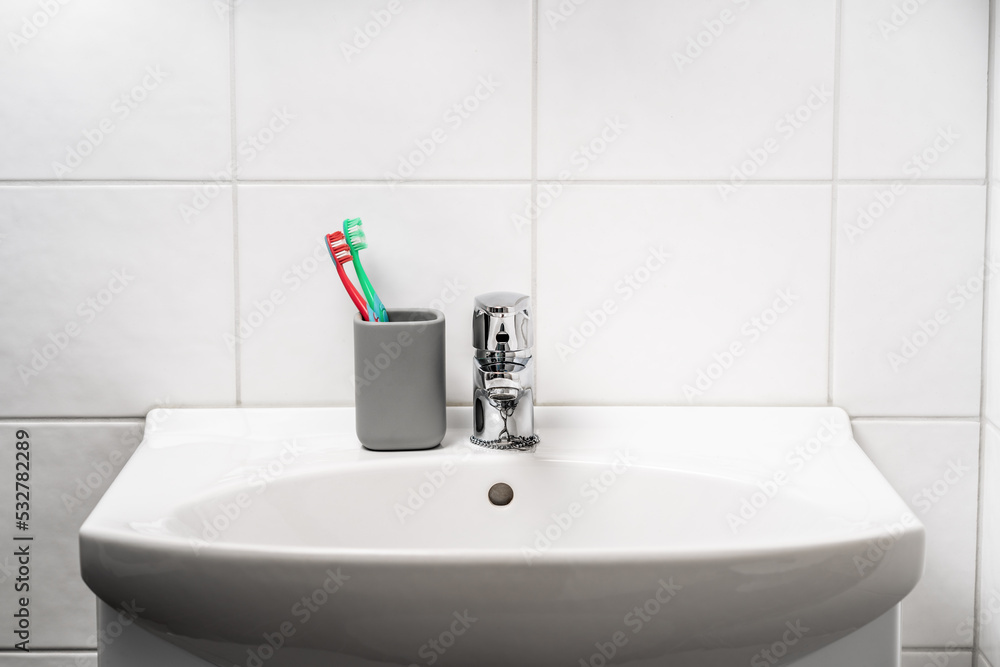Toot brush cup in bathroom and toilet sink. Toothbrush in clean ...