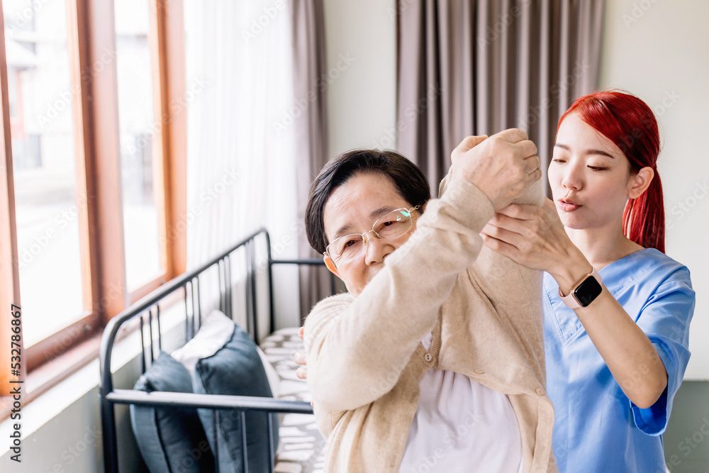 Nurse caregiver wearing scrubs exercises with a senior Asian woman to ...