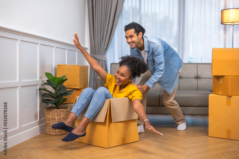Young couple having fun on moving day. Happy first time buyers playing ...