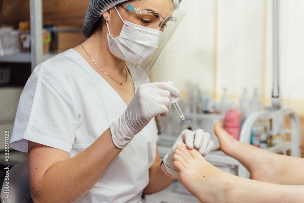 Podologist female doctor in mask on face, making procedure for foot ...