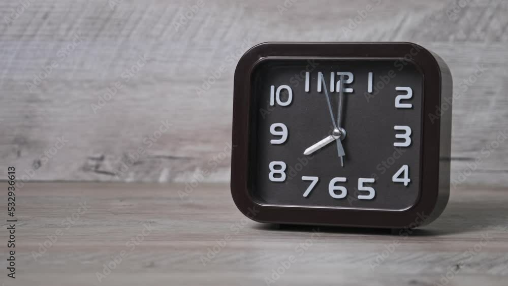 The pointer clock on wooden table shows time 8 o'clock. Arrow brown ...