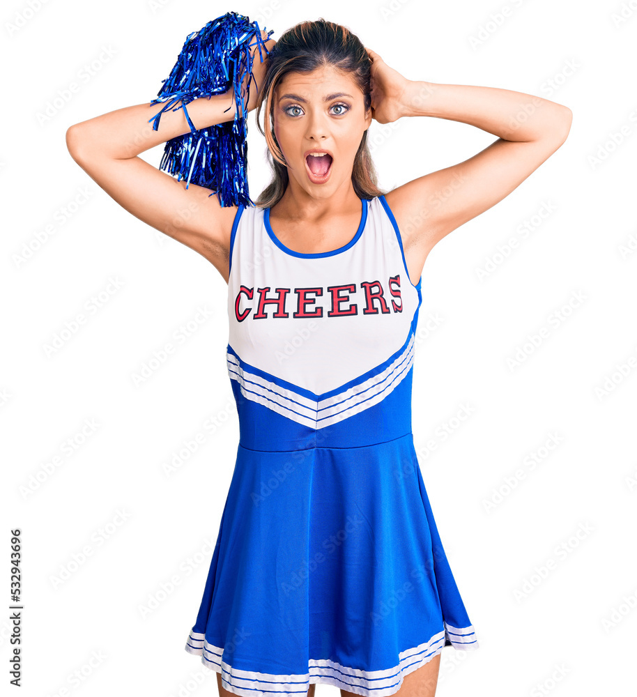 Young beautiful woman wearing cheerleader uniform crazy and scared with ...