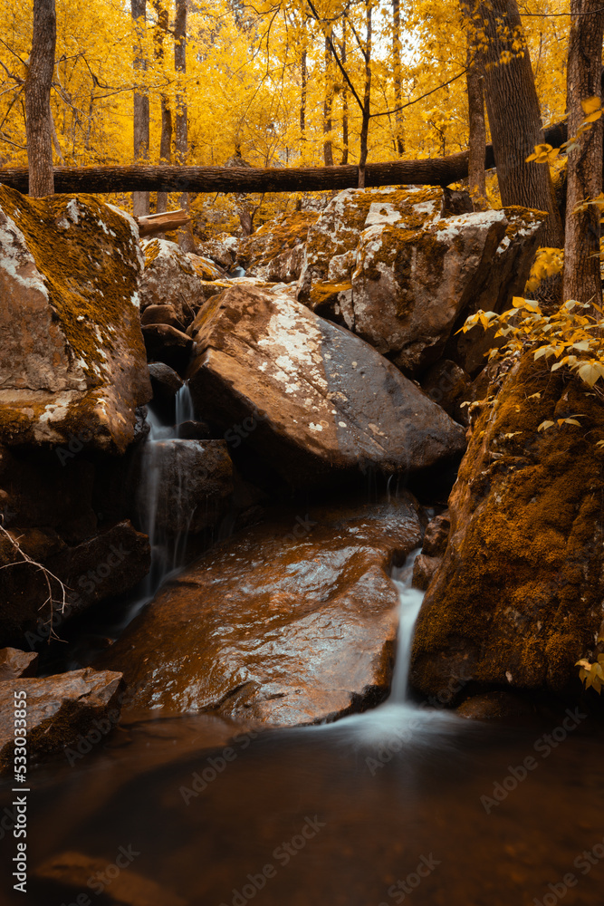 Water cascade flows over large mountain boulders covered with yellow moss in autumn. Stock Photo ...