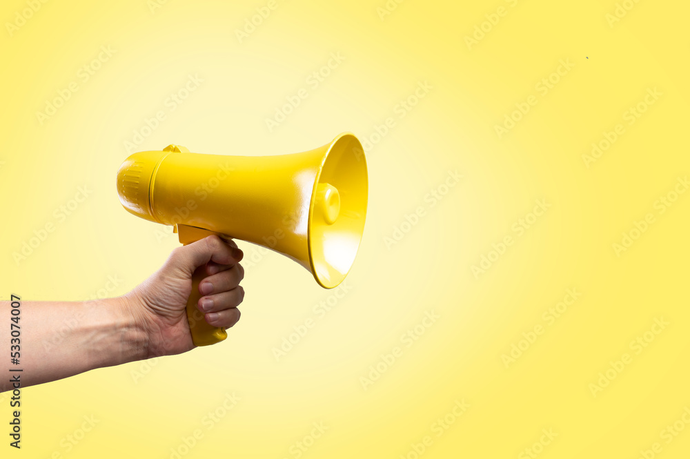Yellow megaphone in a man's hand on a yellow background. Minimalism ...