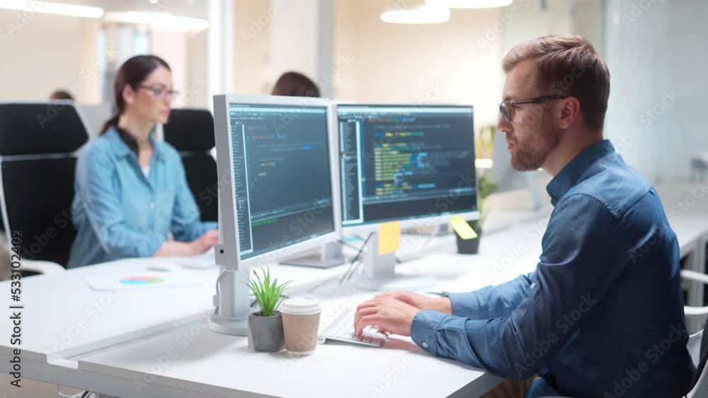 Young Caucasian IT programer working on desktop computers in data ...