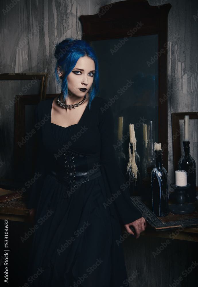 Indoors portrait of gorgeous goth girl in black dress. Blue-haired ...