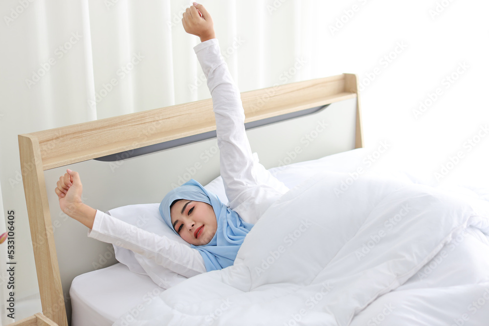 Beautiful asian woman in muslim wearing white sleepwear lying on bed ...