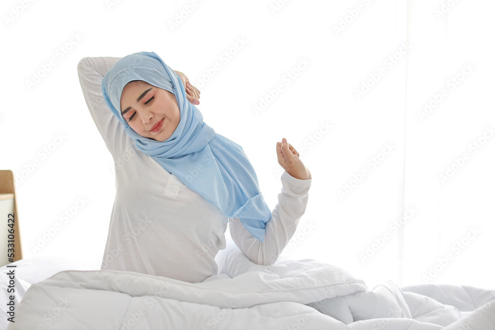 Beautiful asian woman wearing white muslim sleepwear sitting on bed ...