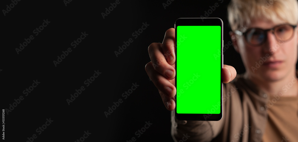 guy 25 years old holds in his hand a smartphone mockup with a chroma ...