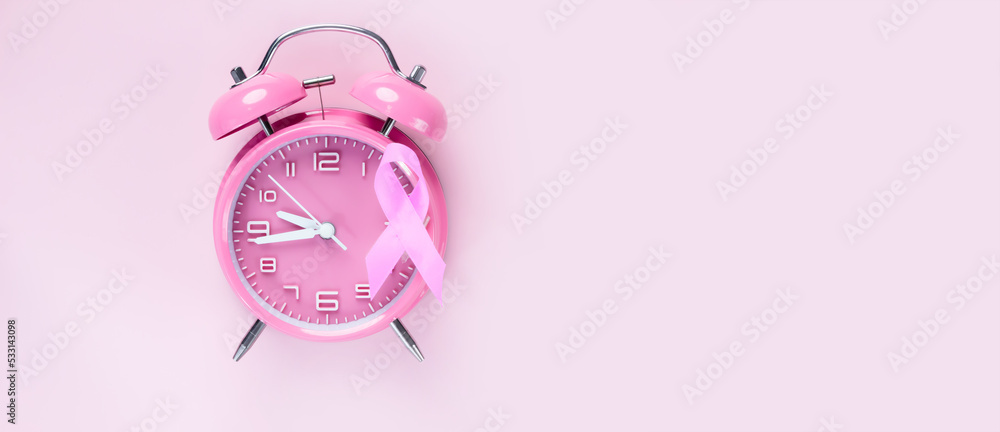 Pink bow ribbon is attached on pink alarm clock to encourage a breast ...