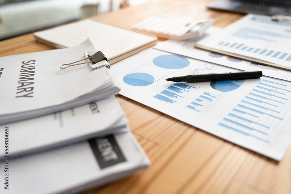 Paper report. Blue graphs and charts. Business reports and a pile of ...