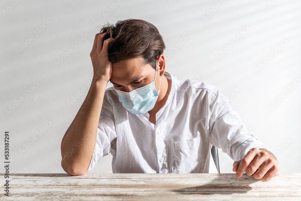 confused asian man overthinking sitting alone wear mask. despair home ...
