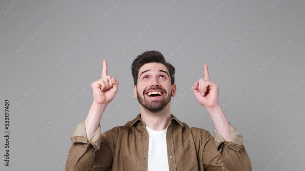 Young promoter man he wear brown shirt pointing fingers hands overhead ...