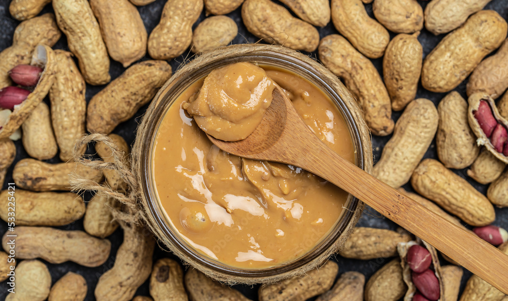 peanut paste in an open jar. creamy peanut butter peanuts scattered ...