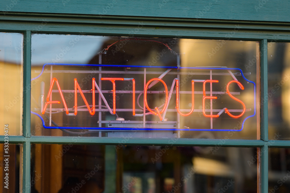 Shop window neon sign spelling antiques in red with green wood window ...