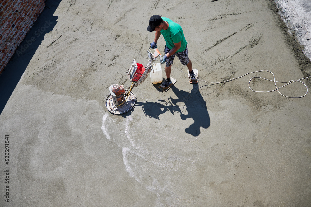 Aerial view of man builder using troweling machine while screeding ...