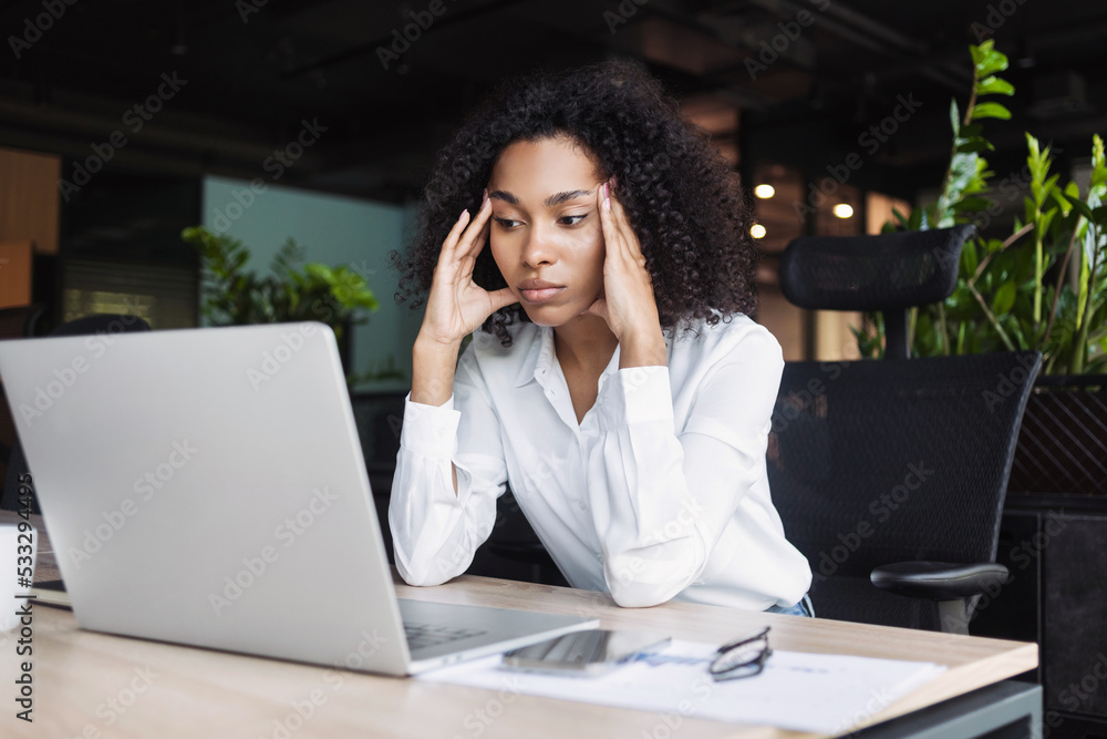 Stressed business woman sitting at office workplace looking at laptop ...
