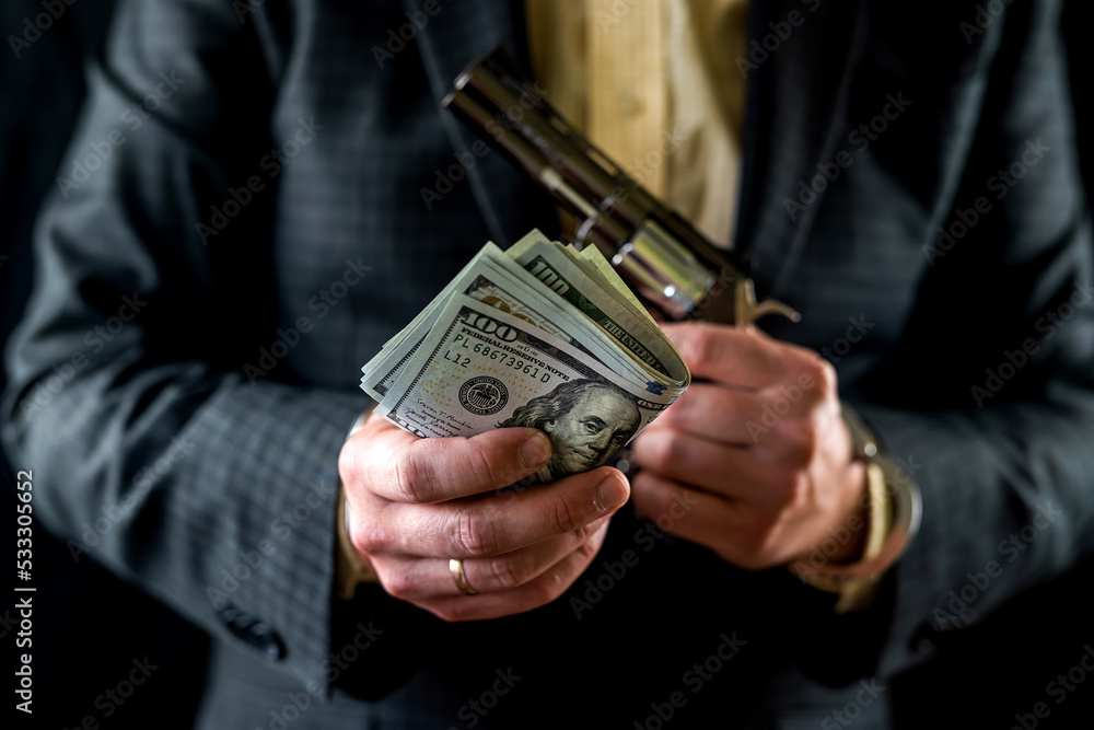 cropped photo of man in suit handing black gun and wad of dollars ...