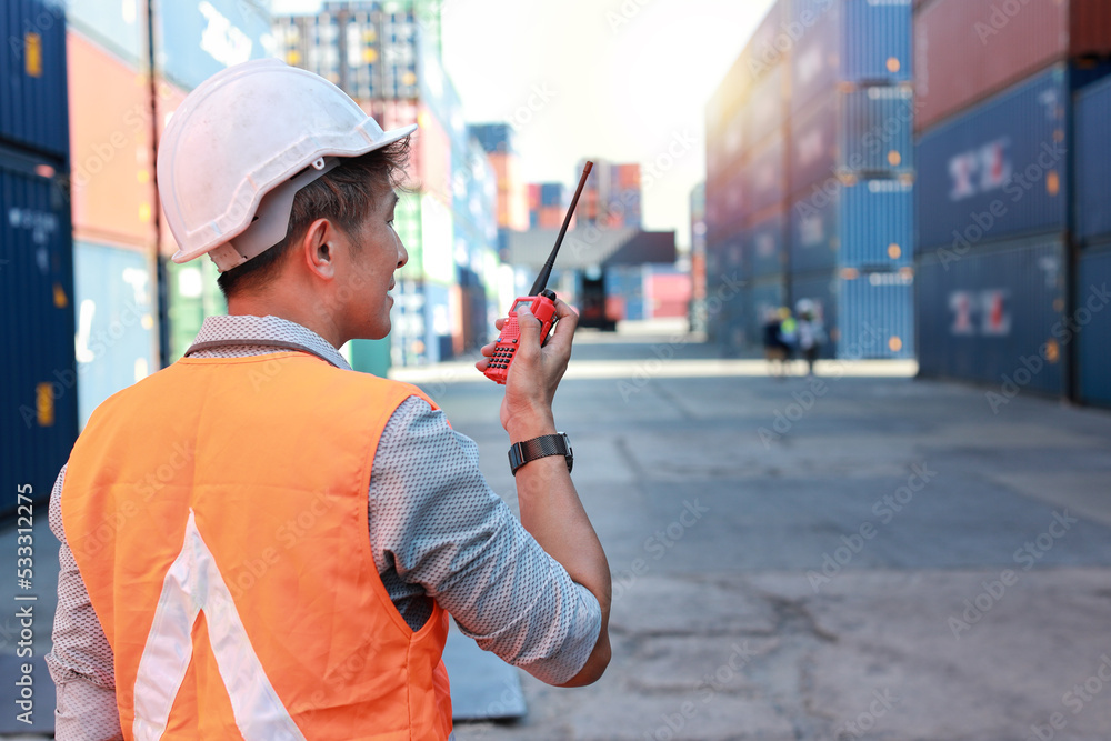 Rear view foreman using walkie talkie radio control loading containers ...