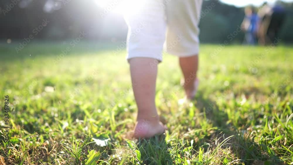 baby running in the park with bare feet. close-up of the kid leg runs ...