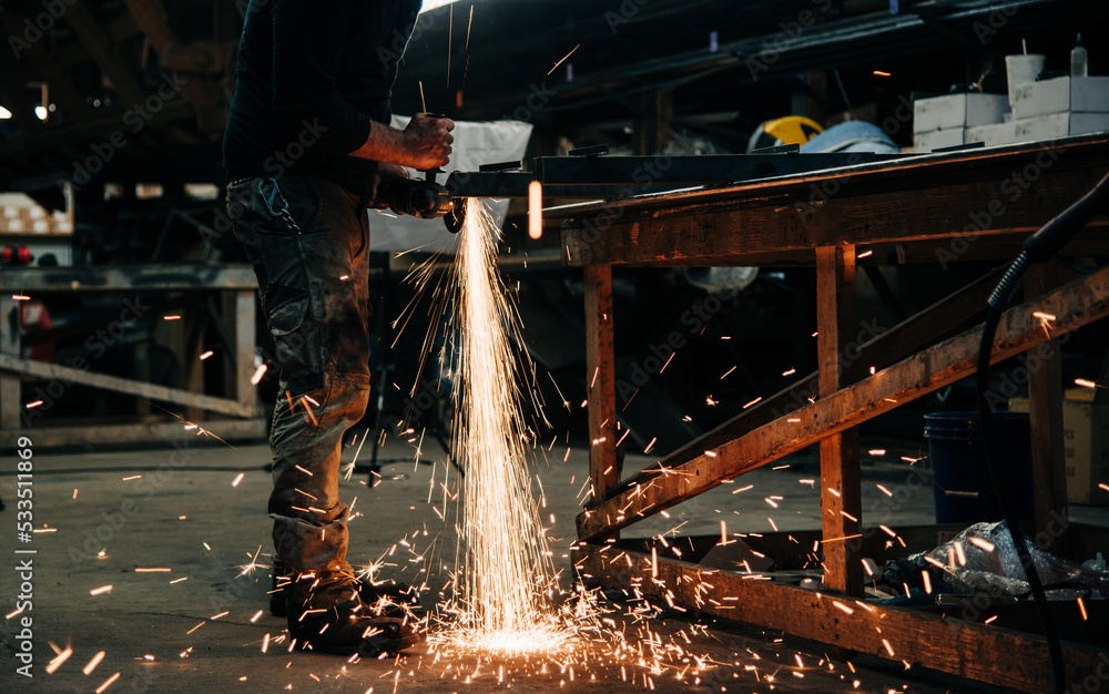 Industrial welder at work cutting steel metal with an angle grinder ...