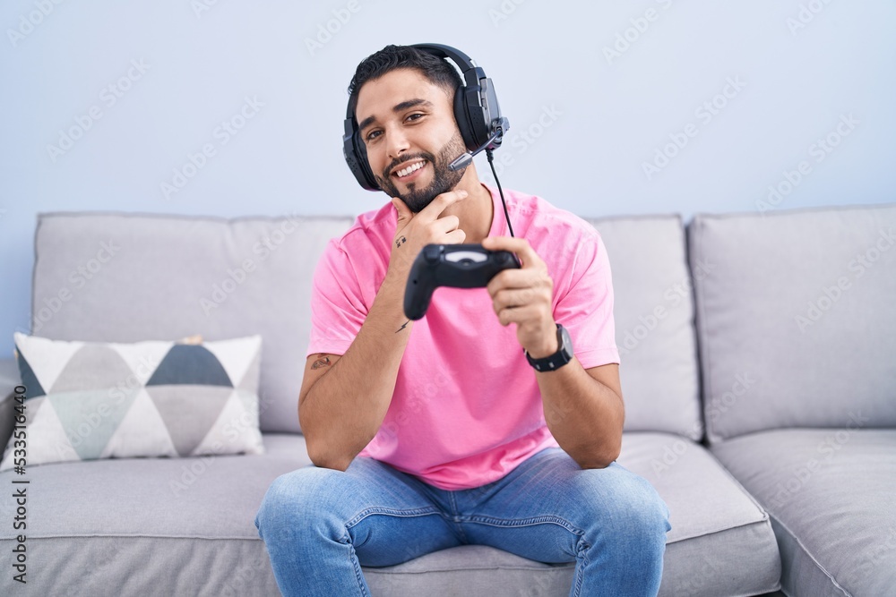Hispanic young man playing video game holding controller sitting on the ...