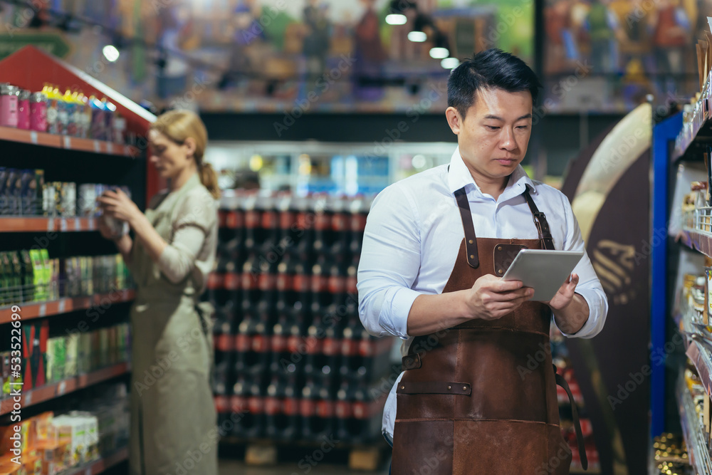 Portrait of young handsome Asian man, shop owner, supermarket worker ...