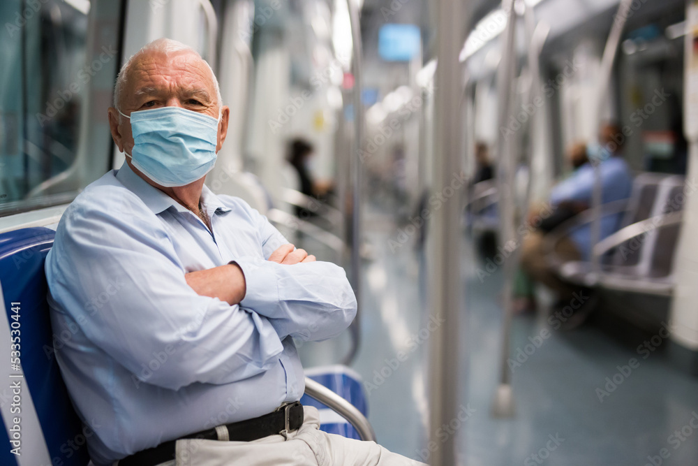 Old European man in face mask sitting inside subway train and waiting ...