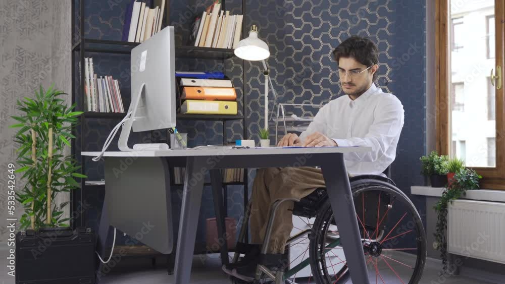 A Disabled Worker Sitting In A Wheelchair Working At The Computer ...