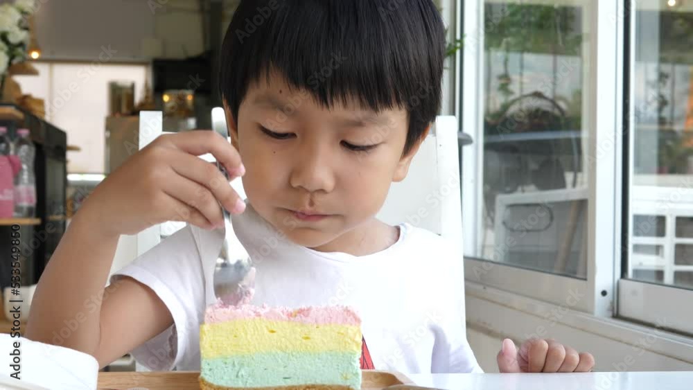 Asian child boy eating delicious cake in bakery shop, hand holding ...