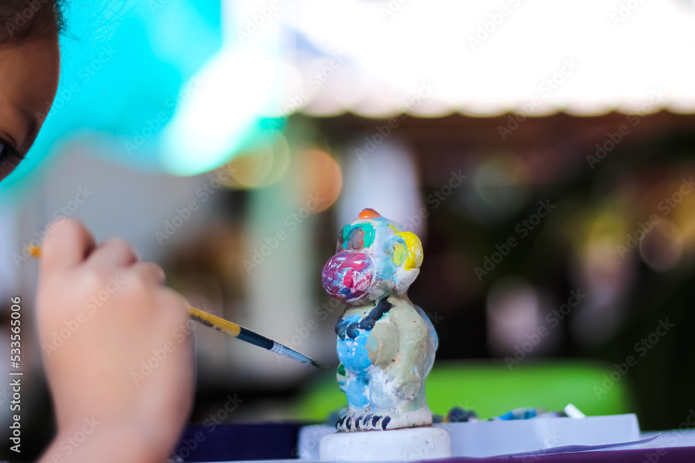 Blurred plaster monkey statue by asian child girl hand painting with ...