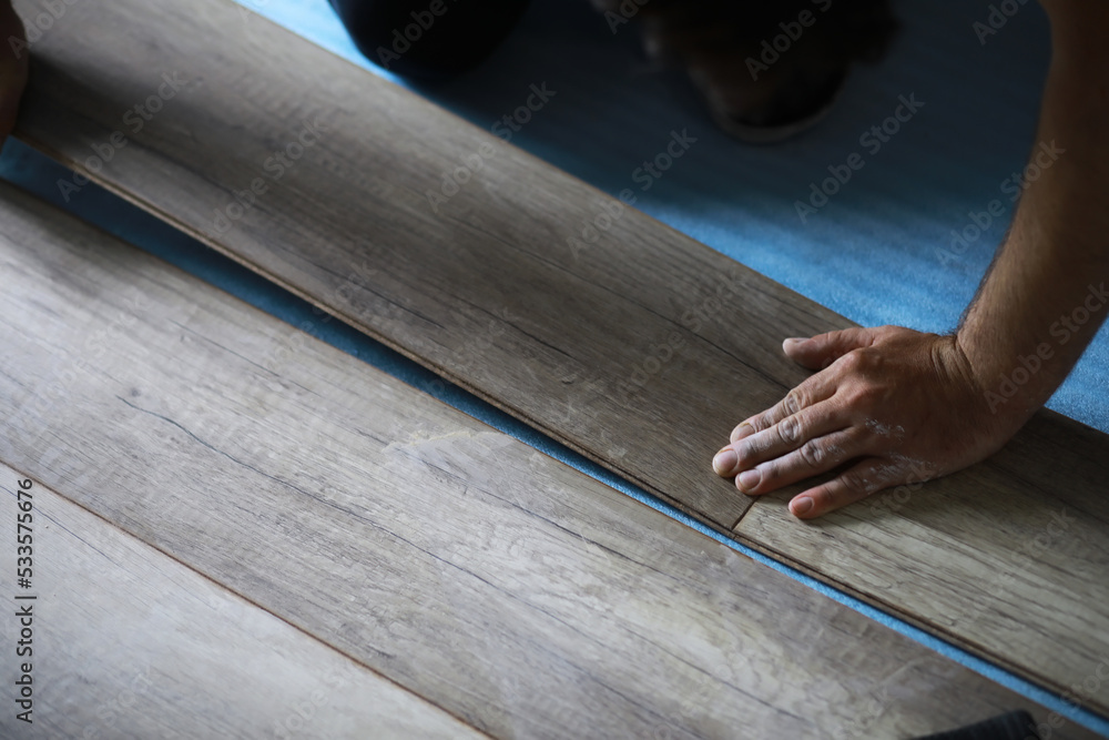 Installing laminated floor, detail on man hands blue wooden tile, over ...
