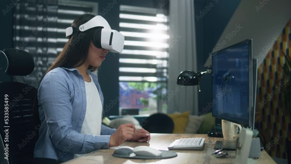 Asian female 3D designer in VR goggles working on pc in 3D modeling program remotely from home ...