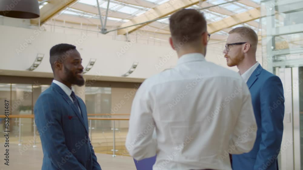 Corporate staff members meet in modern office hallway and talk Stock ...