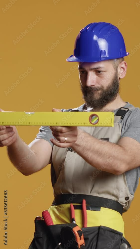 Vertical video: Construction builder working with water level tool to ...