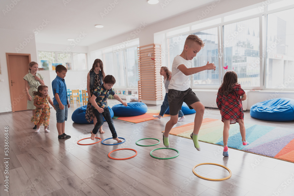 Small nursery school children with female teacher on floor indoors in ...
