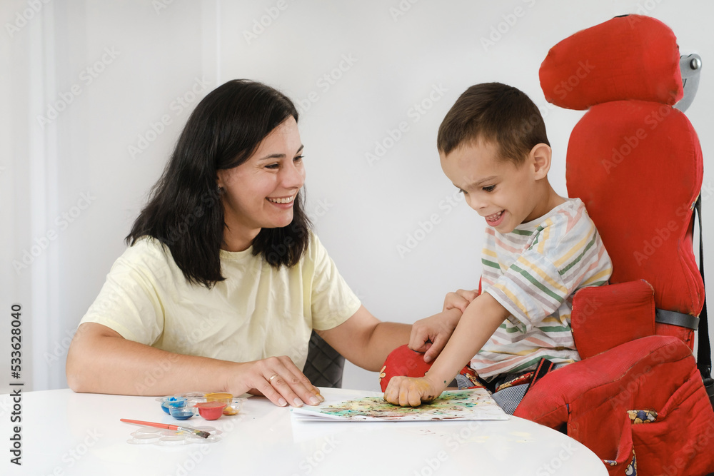 Child with cerebral palsy painting with fingers and hands. Happy ...