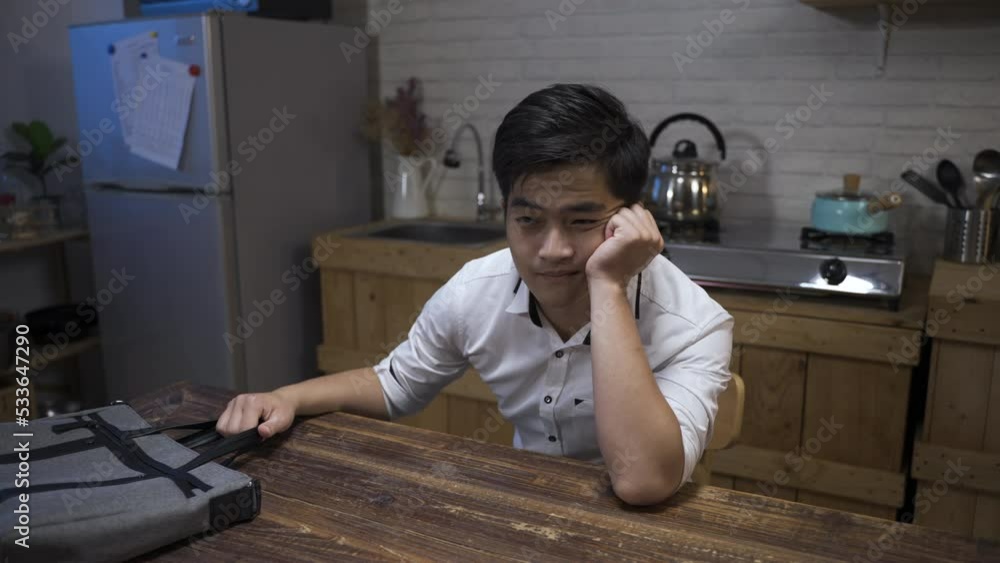 depressed asian male manager arriving home after work is sitting down ...