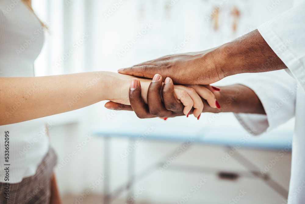 Friendly male doctor's hands holding female patient's hand for ...