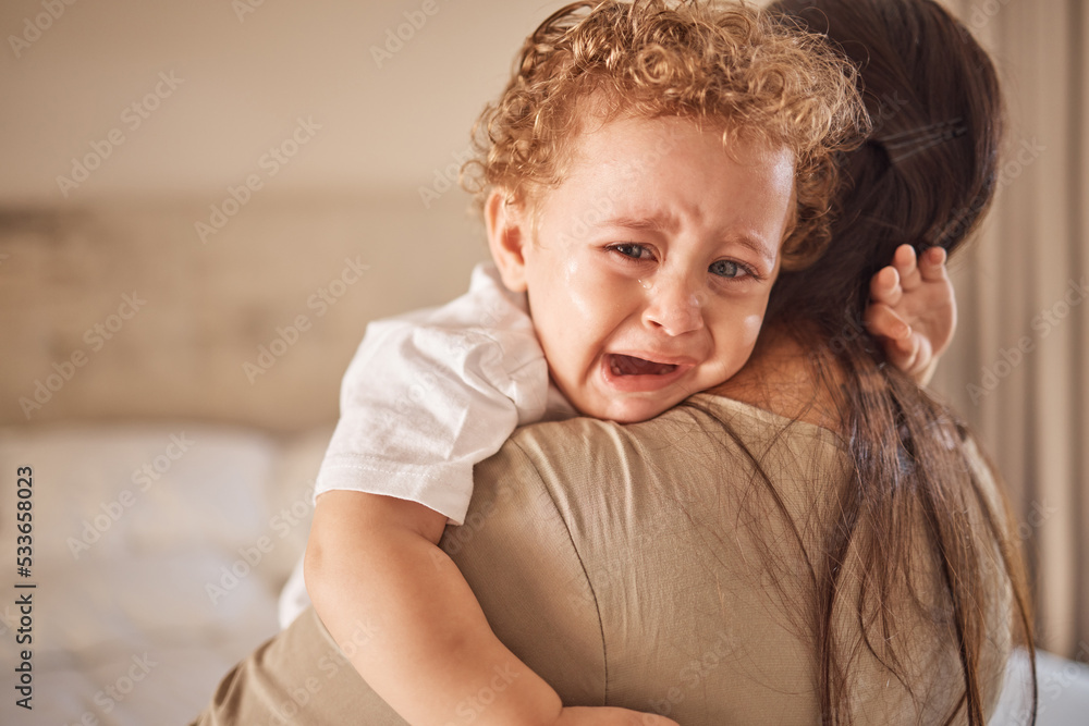 Mother and crying baby in a bedroom with portrait of sad son looking ...