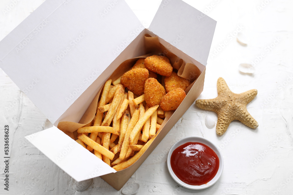 Deep fried fish nuggets in a take-away carton box and a tomato sauce ...
